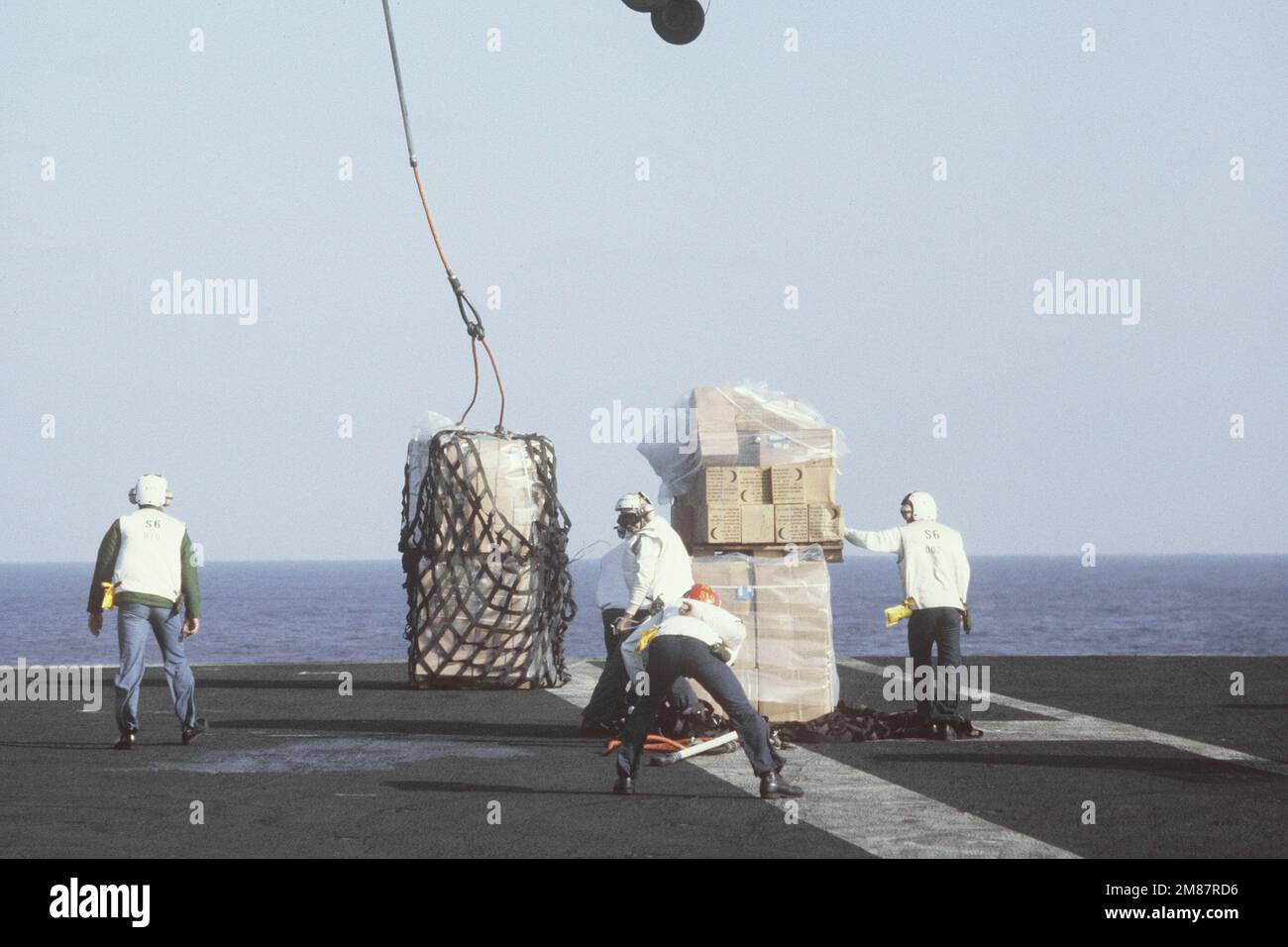 Crew members remove cargo nets from supplies that were delivered by a ...