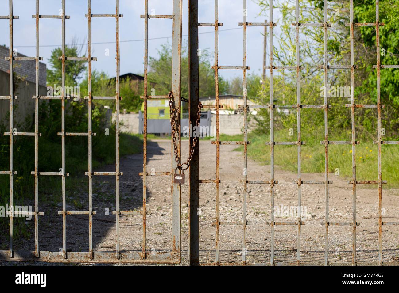 Old rusty iron gate on chain and lock. Closed metal gates. Protection ...