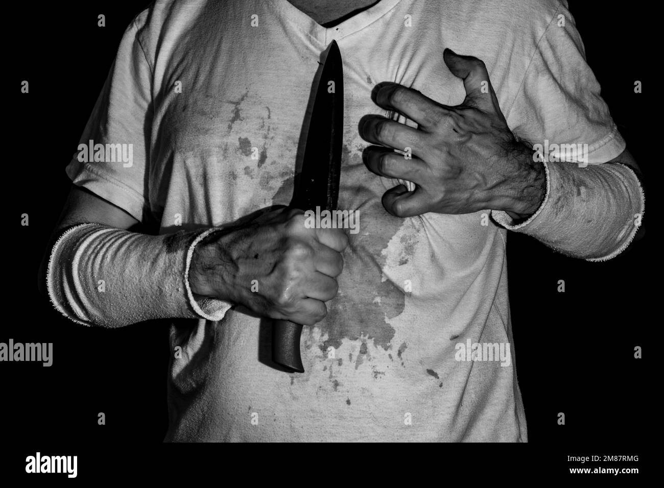 Black and white portrait of a man holding a knife against his chest ...
