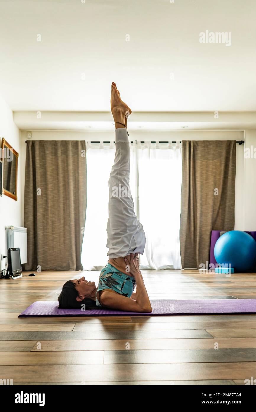 Side view of a woman practicing yoga, doing Shoulderstand pose. Yoga ...