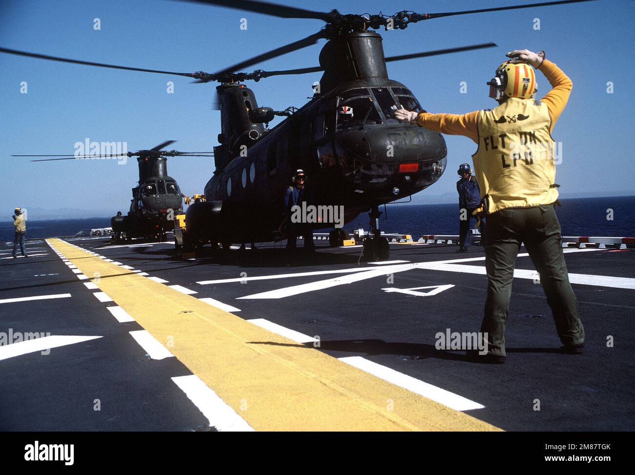 A flight deck leading petty officer (LPO) signals to the pilot of a CH ...
