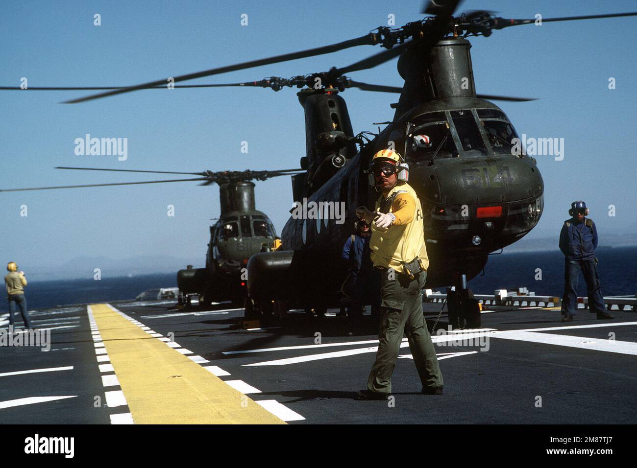 A plane director stands by as a CH-46 Sea Knight helicopter prepares ...