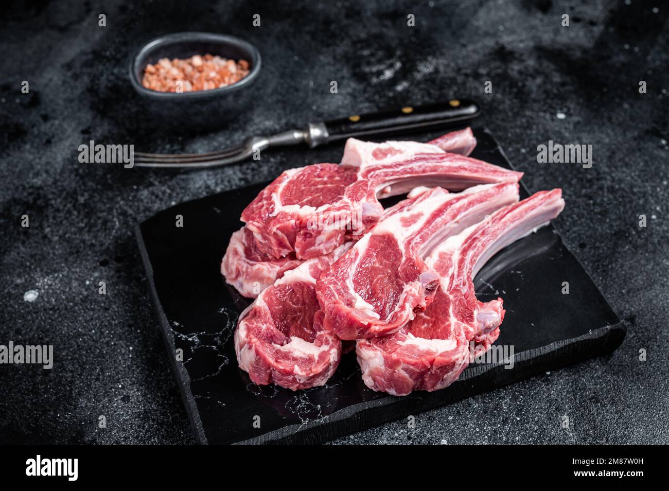 Uncooked lamb mutton chops, raw meat steaks. Black background. Top view ...