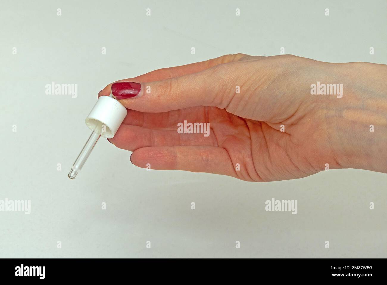 Female hand holding pipette dropper against white background Stock ...