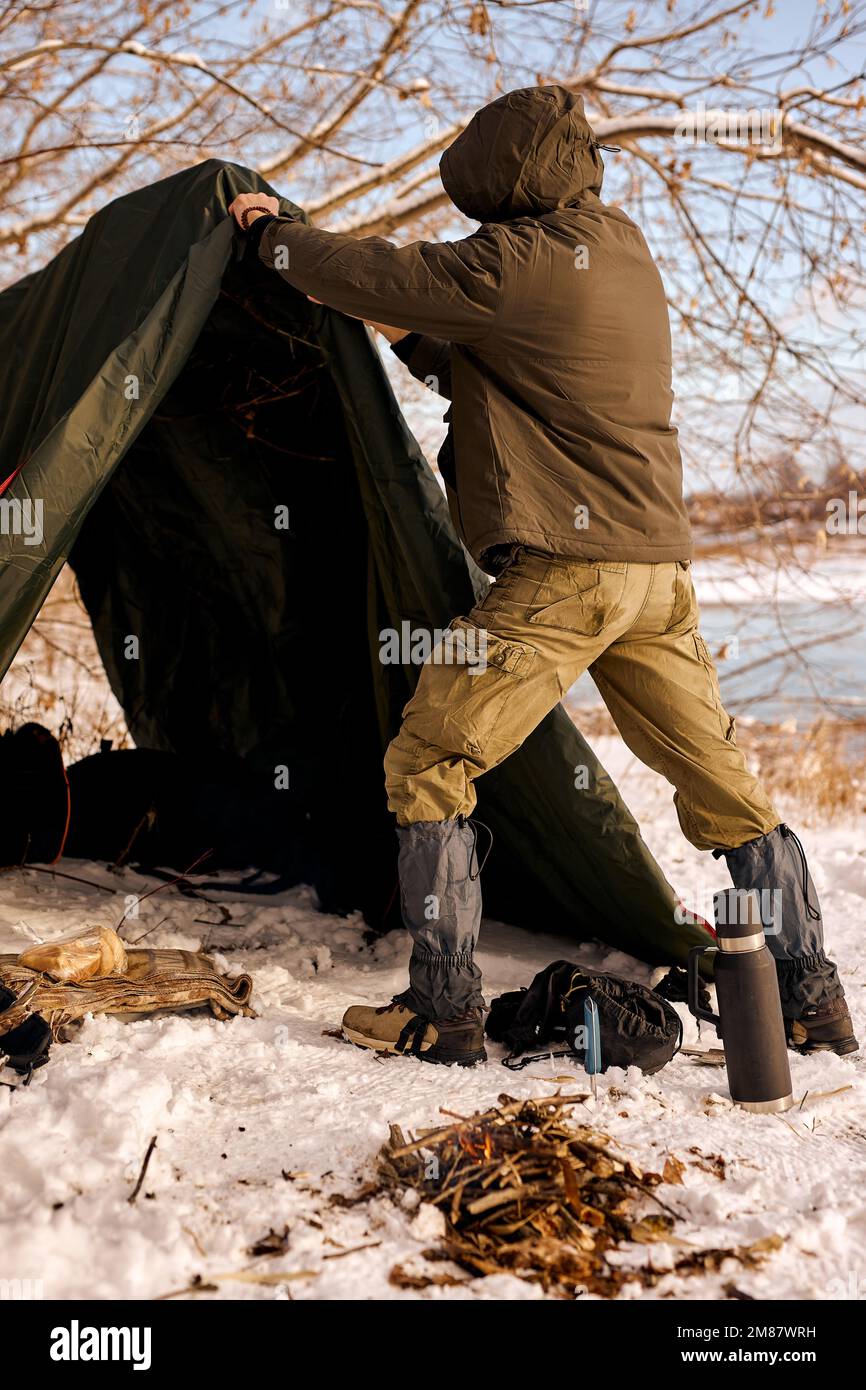 rear view on male hiker setting up tent in forest, pitching in forest ...