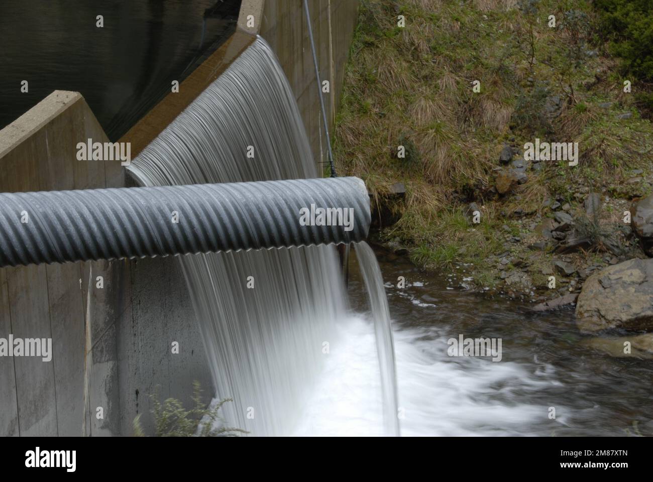 Flowing water over dam and out of corrugated pipe Stock Photo - Alamy