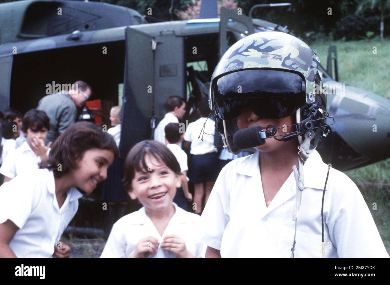 A Costa Rican boy tries on a flight helmet as other children study a ...