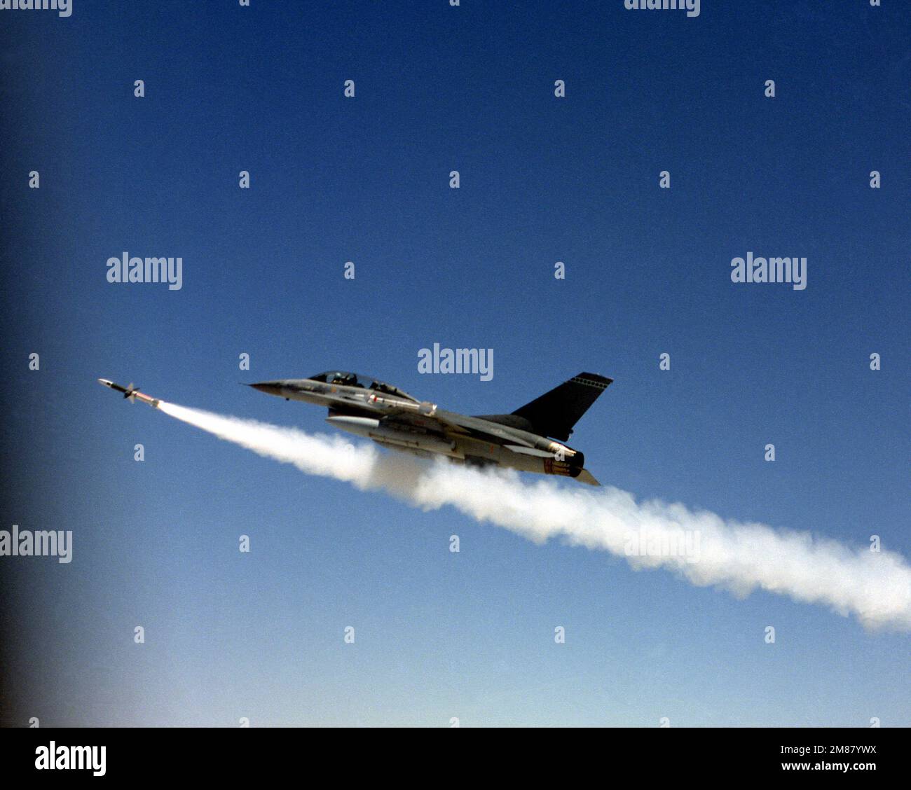 An air-to-air left side view of an F-16B Fighting Falcon aircraft ...