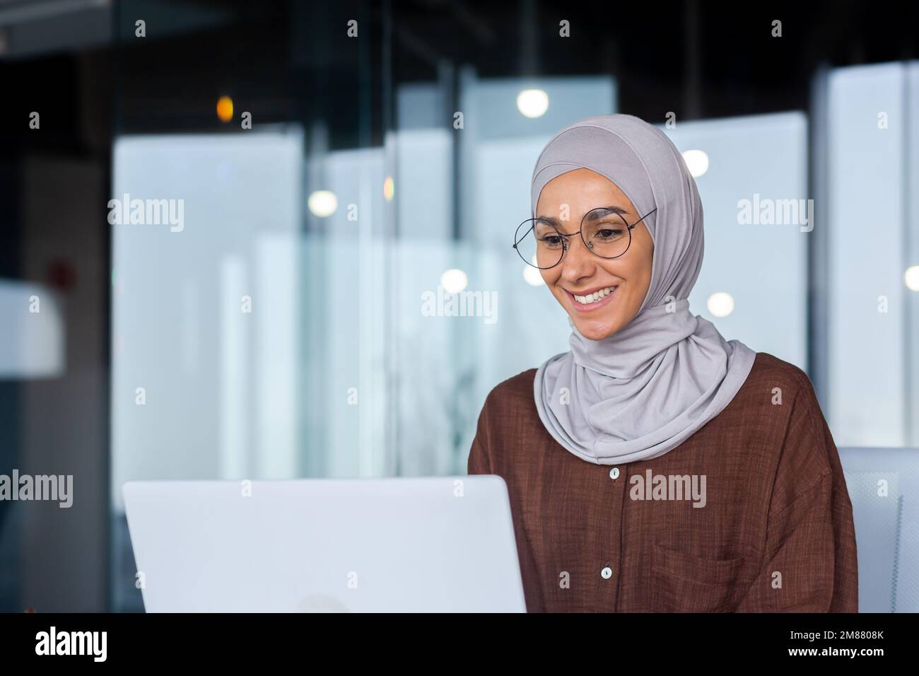Young beautiful muslim woman in hijab working inside modern office ...