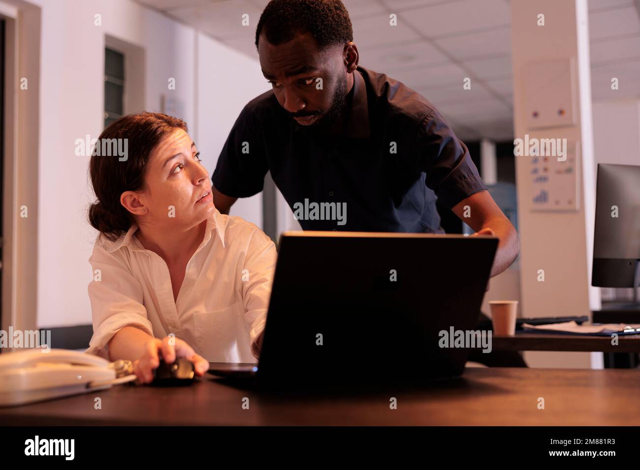 Man helping coworker analyzing report on laptop in office, colleagues ...