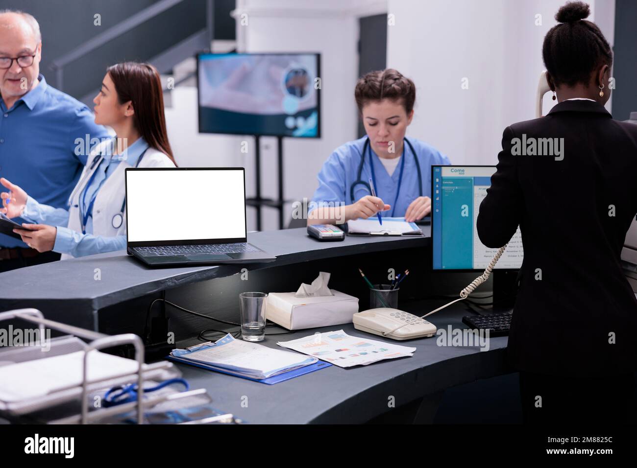 Receptionist talking with nurse discussing medical report during ...