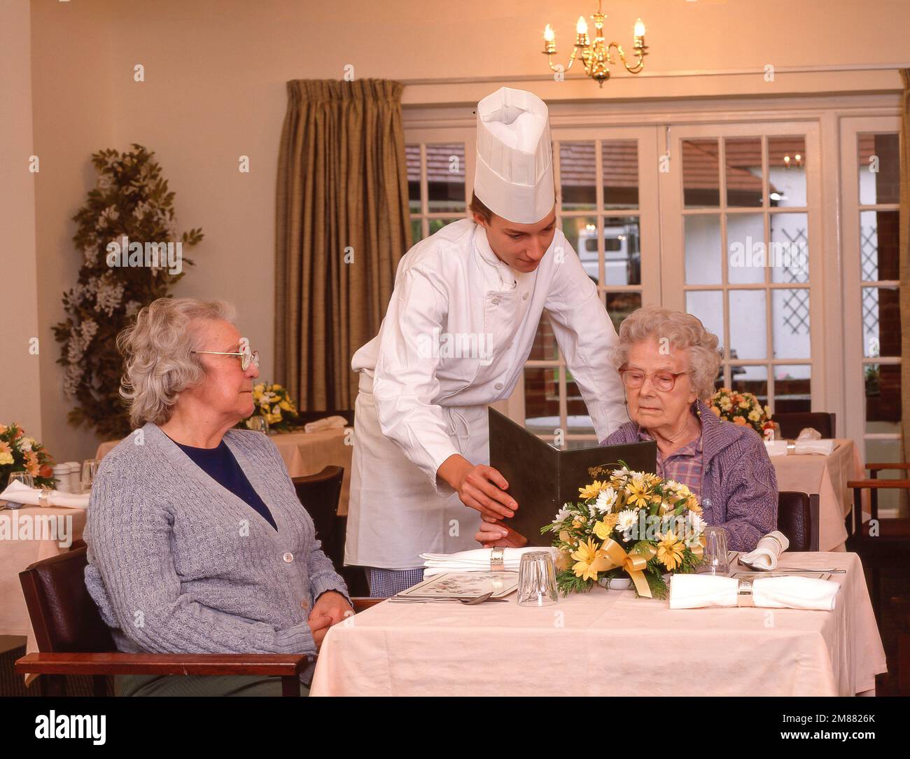 Chef showing residents dinner menu in nursing home dining room, Surrey ...