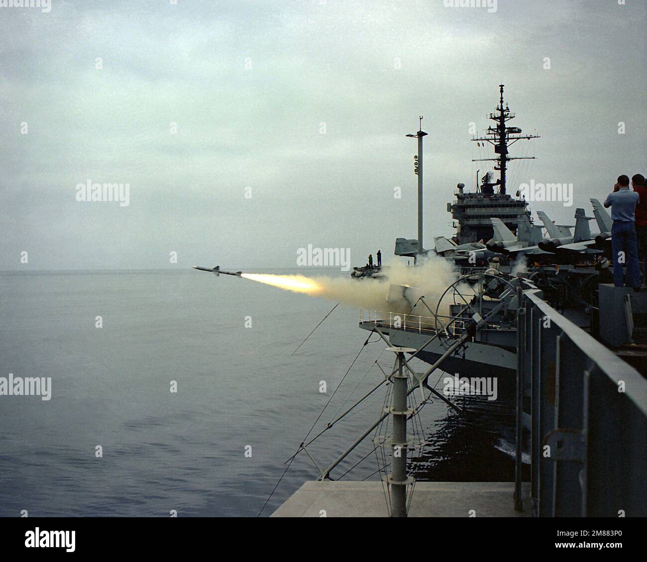 As seen from the ship's bow, a RIM-7 Sea Sparrow missile is launched ...