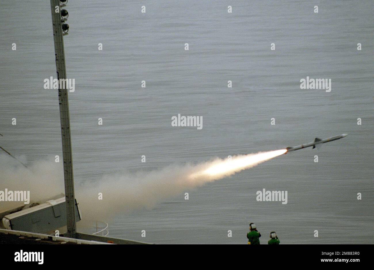 Two flight deck crewmen watch as a RIM-7 Sea Sparrow missile is ...