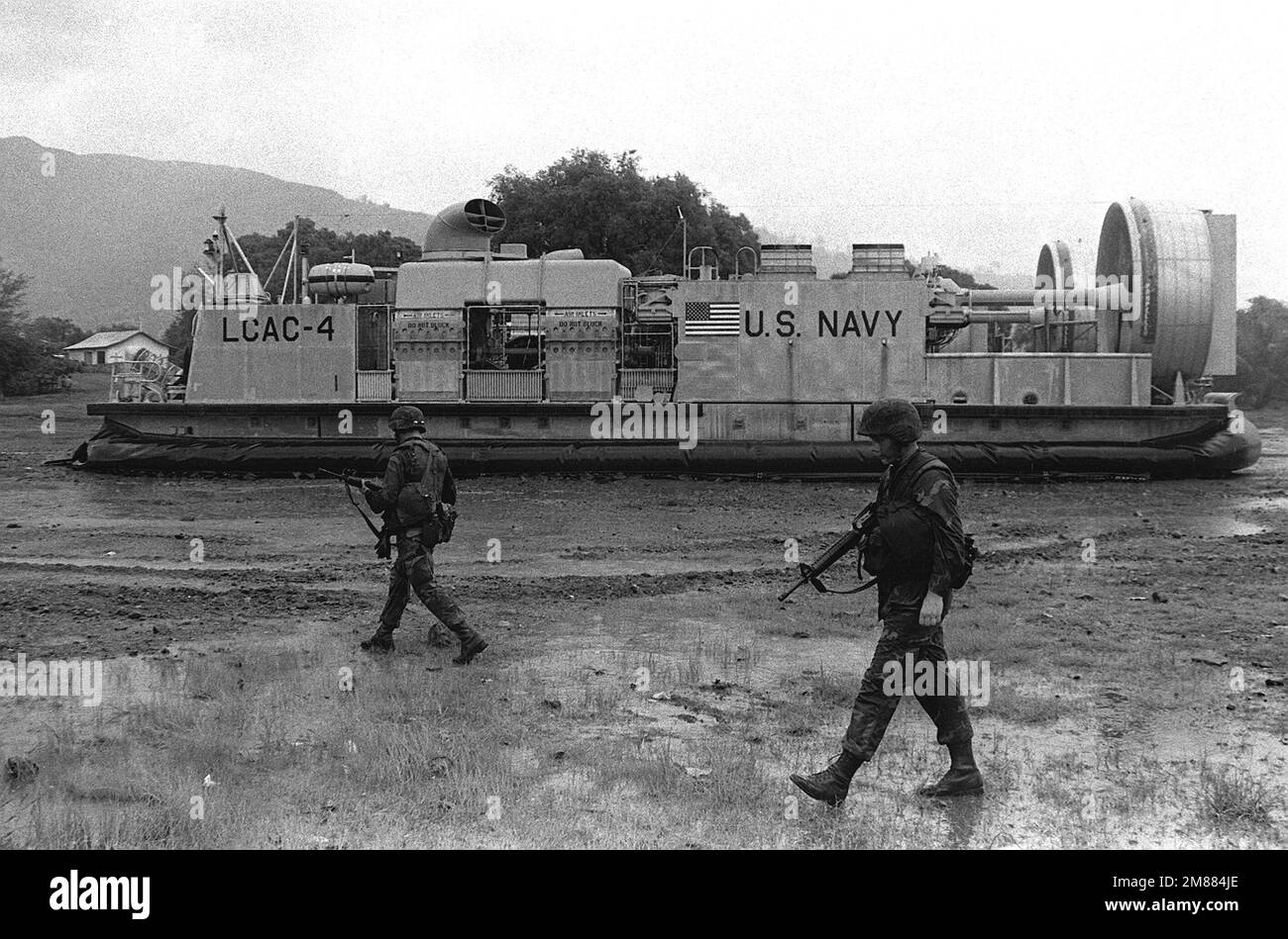 Marines from Co. A, 1ST Bn., 9th Marine Regt., walk by an Assault Craft ...