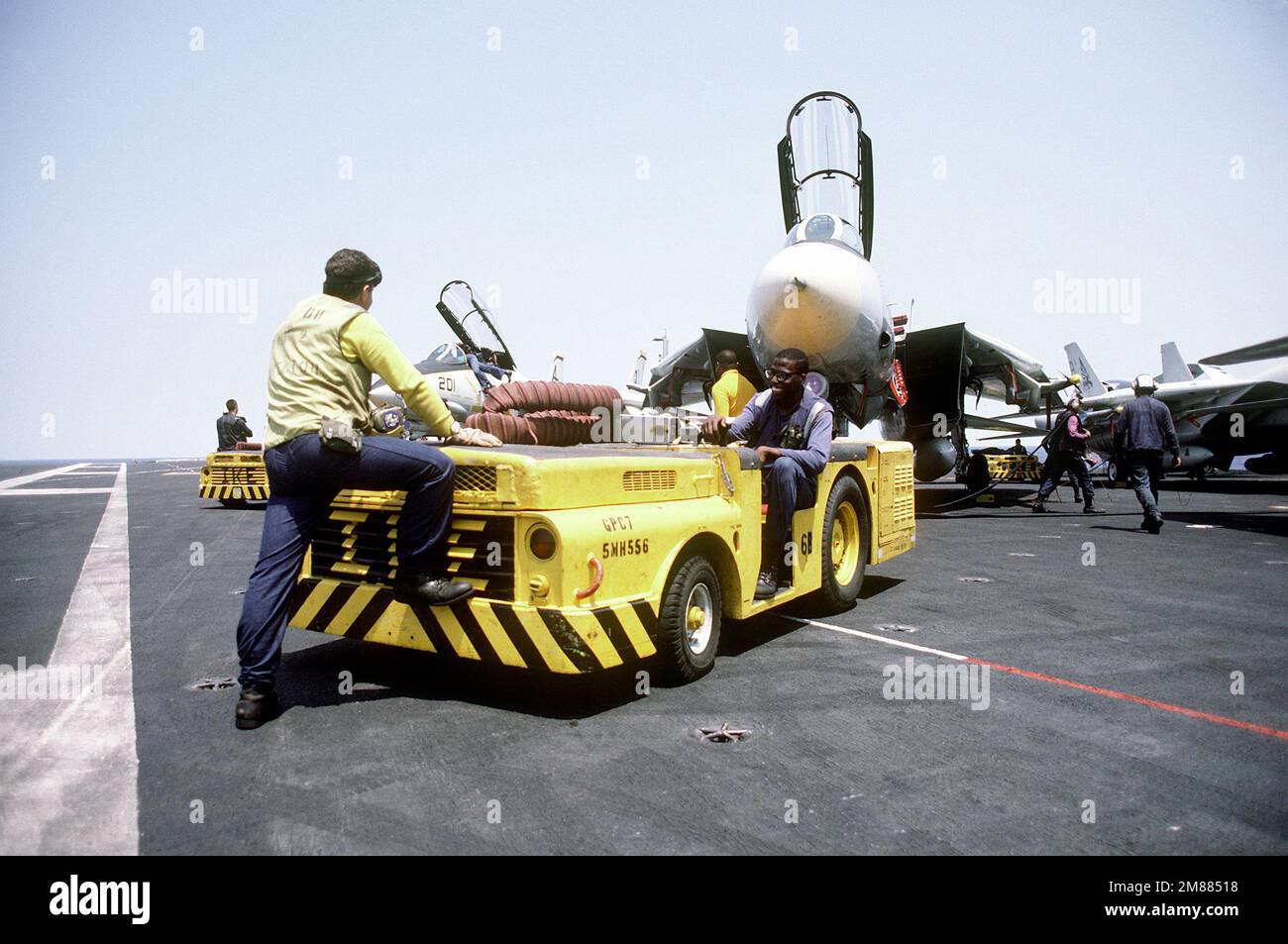 Crewmen use MD-3A tow tractors to position F-14A Tomcat aircraft on the ...