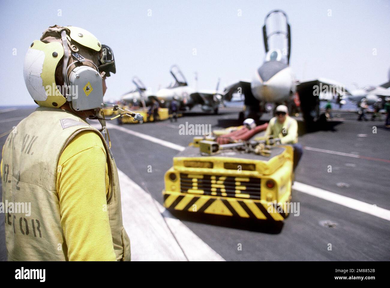 Flight deck crewmen use MD-3A tow tractors to position an F-14A Tomcat ...