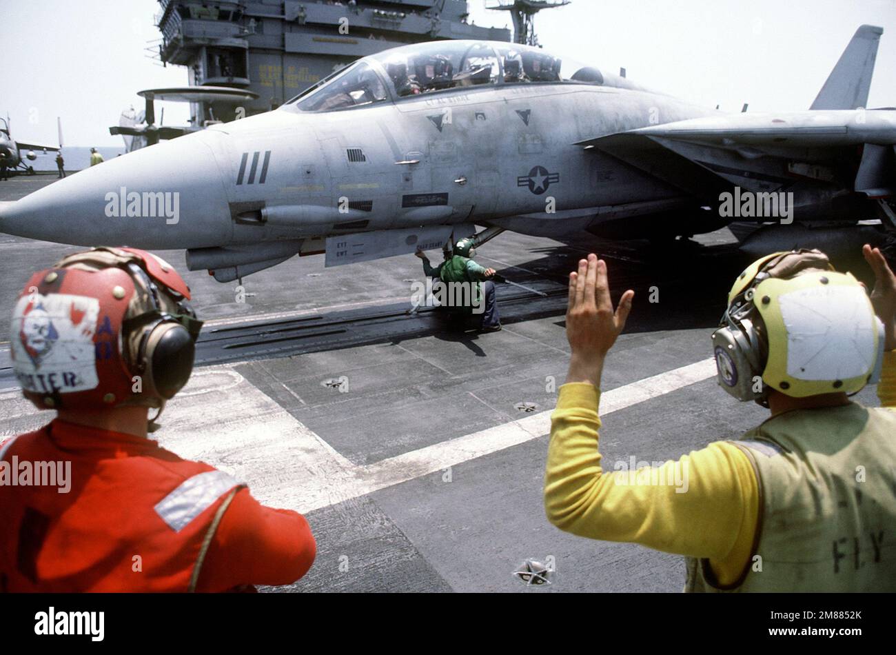 A plane director signals instructions to the pilot of an F-14A Tomcat ...