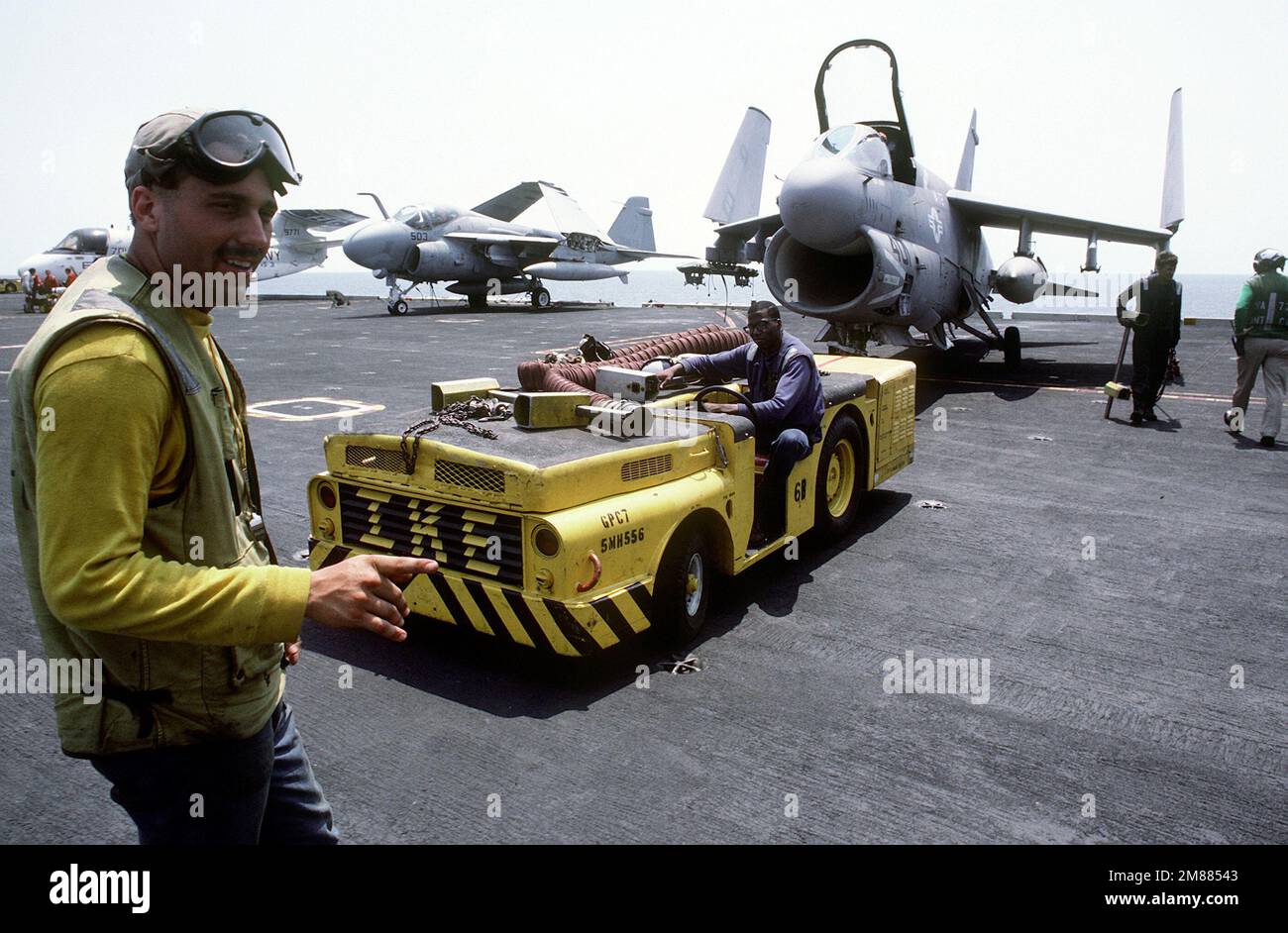 An MD-3A tow tractor is used to tow an A-7E Corsair II aircraft to a ...