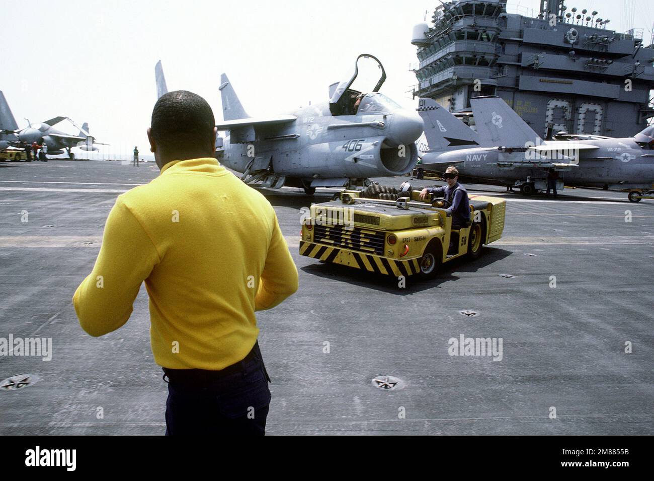 A plane director supervises the towing of an Attack Squadron 72 (VA-72 ...