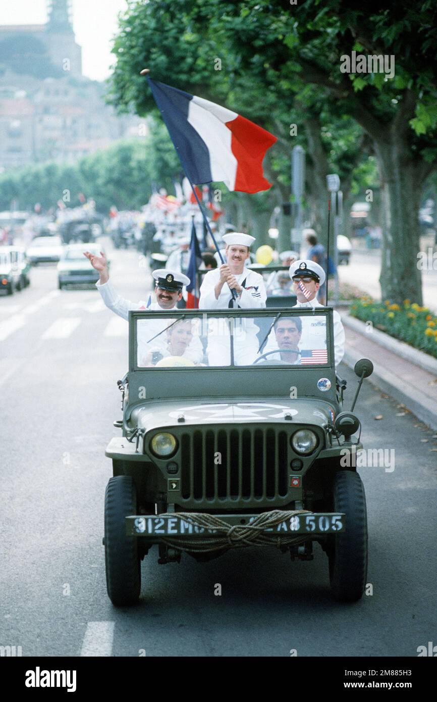 An American sailor waves the French flag from a jeep in a parade of ...