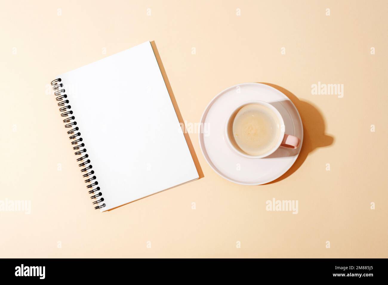 Coffee in cup and spiral notebook on neutral background with sharp ...