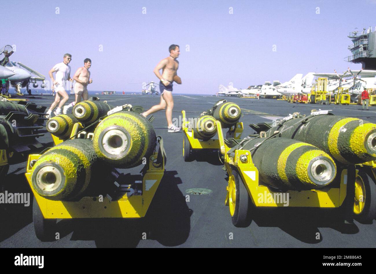 Crew members jog past Mark 82 500-pound high-drag bombs secured on bomb ...