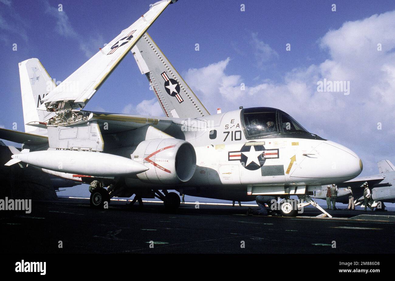 A flight deck crewman attaches an S-3A Viking aircraft to a catapult ...