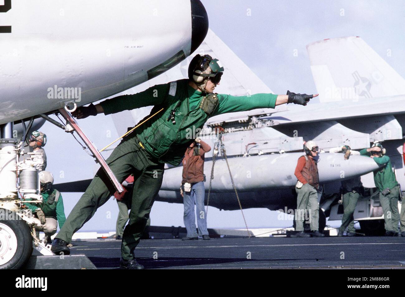 A catapult crewman standing in front of an E-2C Hawkeye aircraft ...