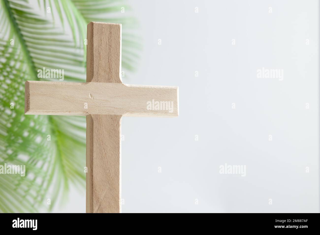 Simple wood Christian cross with palm frond leaves on a white ...