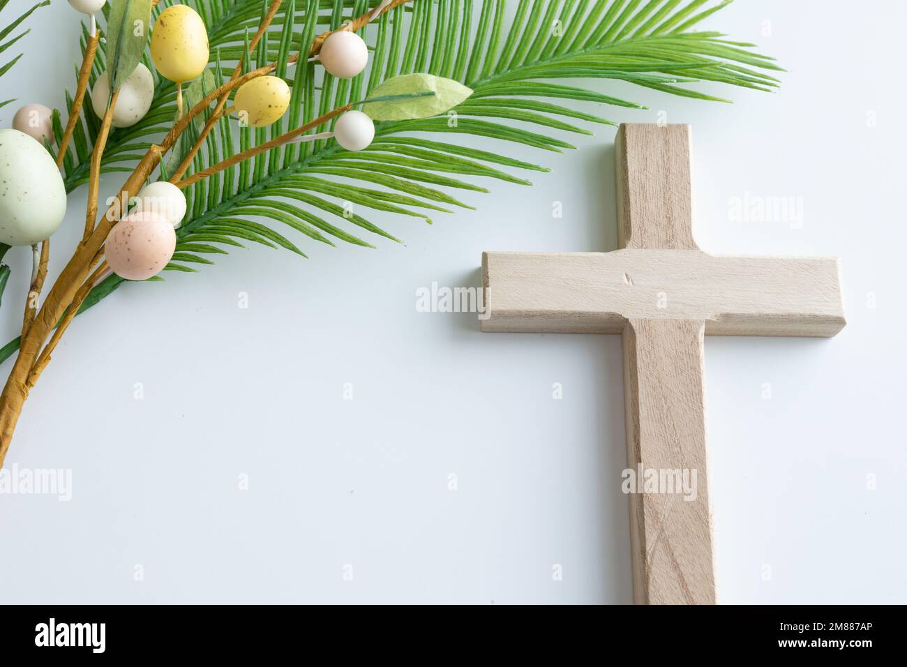 Small wood Christian cross with palm frond leaves and easter eggs on a ...