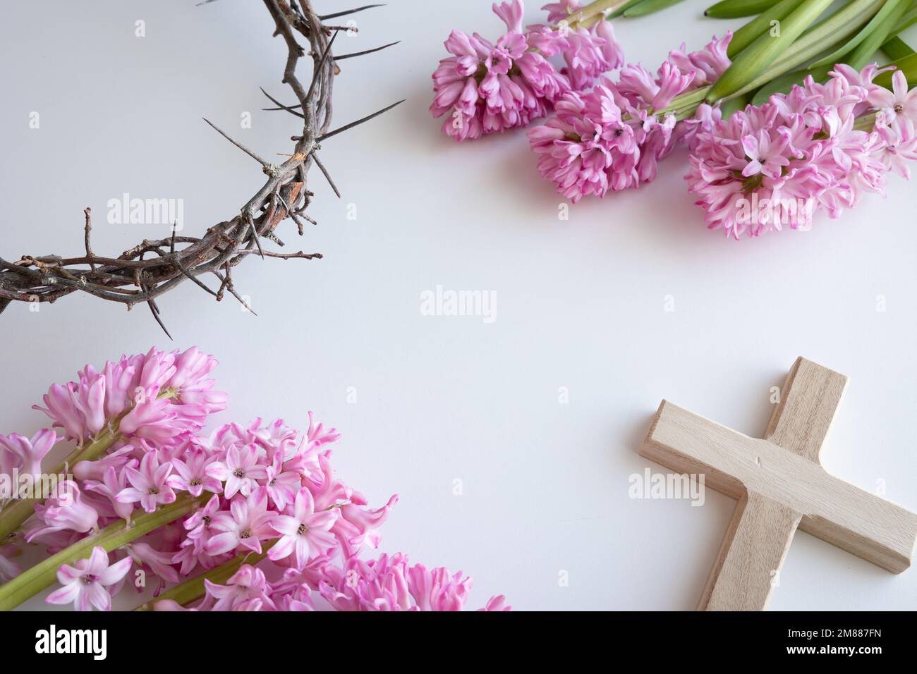 Simple wood cross and crown of thorns with pink hyacinth flowers on a ...