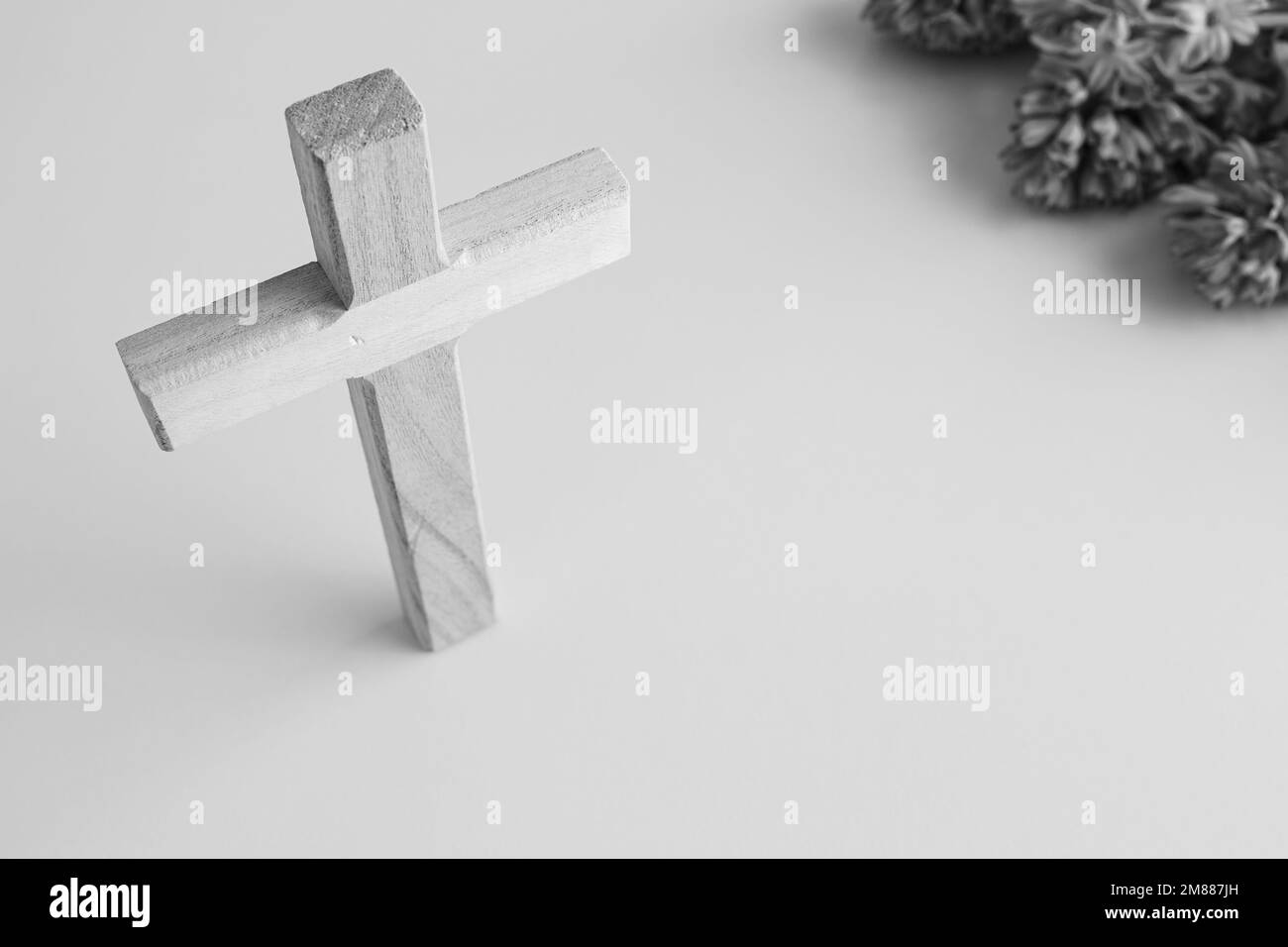 Simple Christian wood cross with a bouquet of flowers on a white table ...