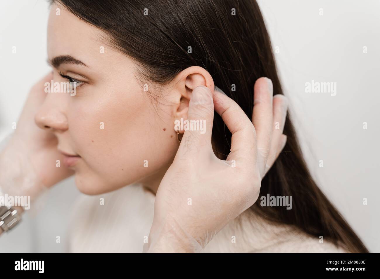 Otoplasty ear surgery. Surgeon doctor examines girl ears before ...