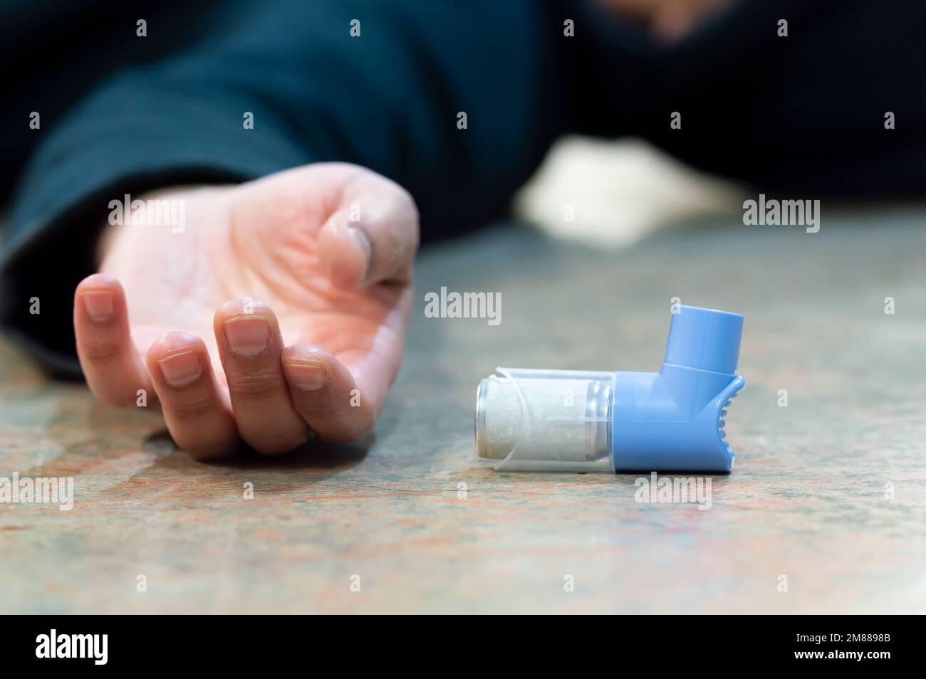 Asthmatic man suffering an asthma attack and on the floor in a dark ...