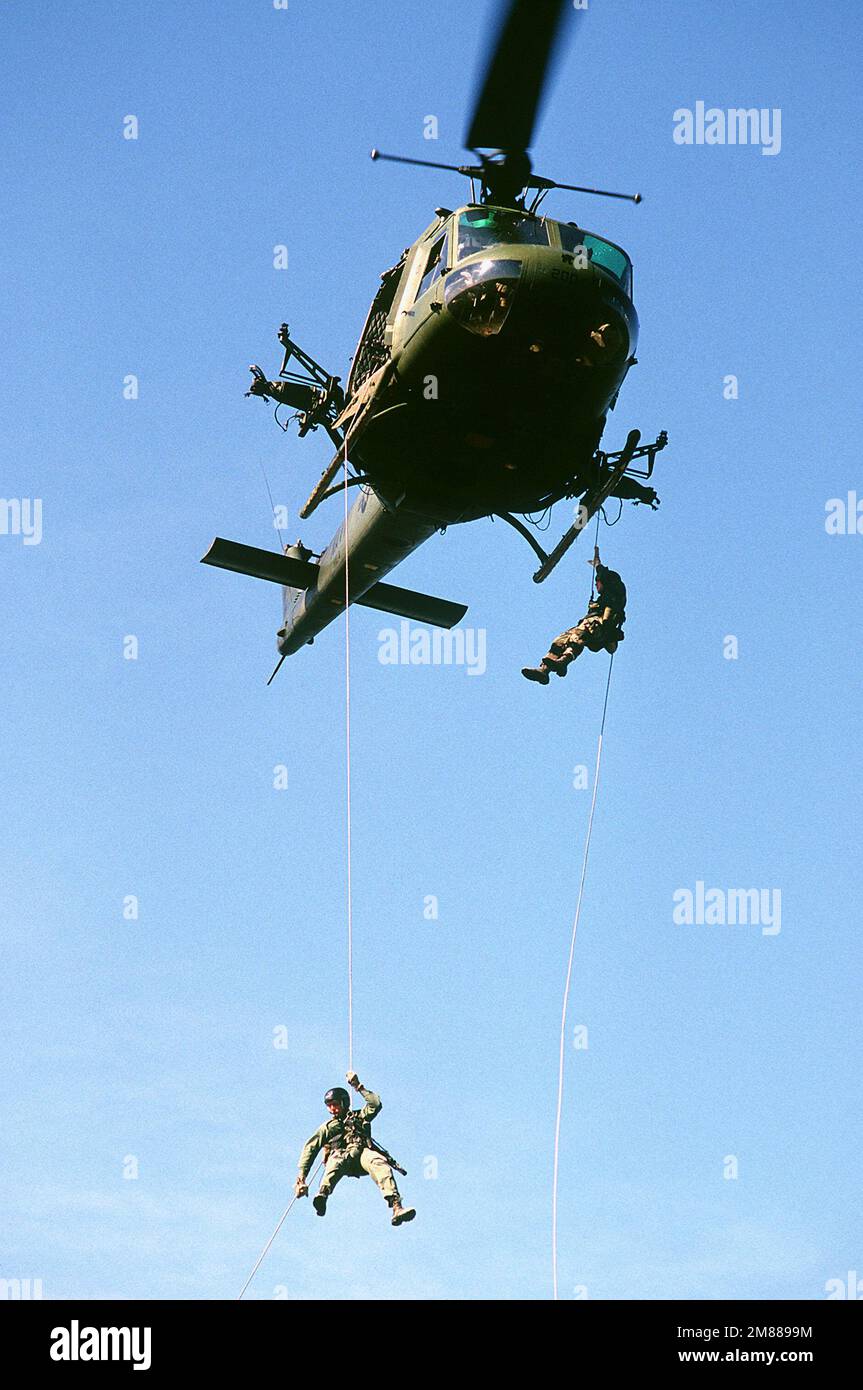U.S. Navy Sea-Air-Land (SEAL) team members rappel from a UH-1 Iroquois ...
