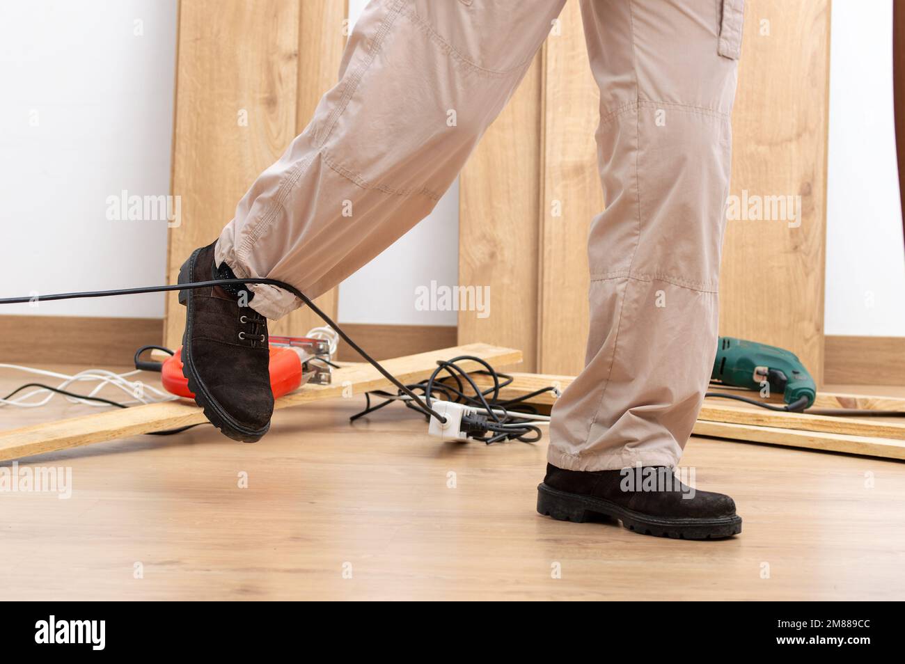 Close up of a carpenter legs stumbling with an electrical cord at home ...