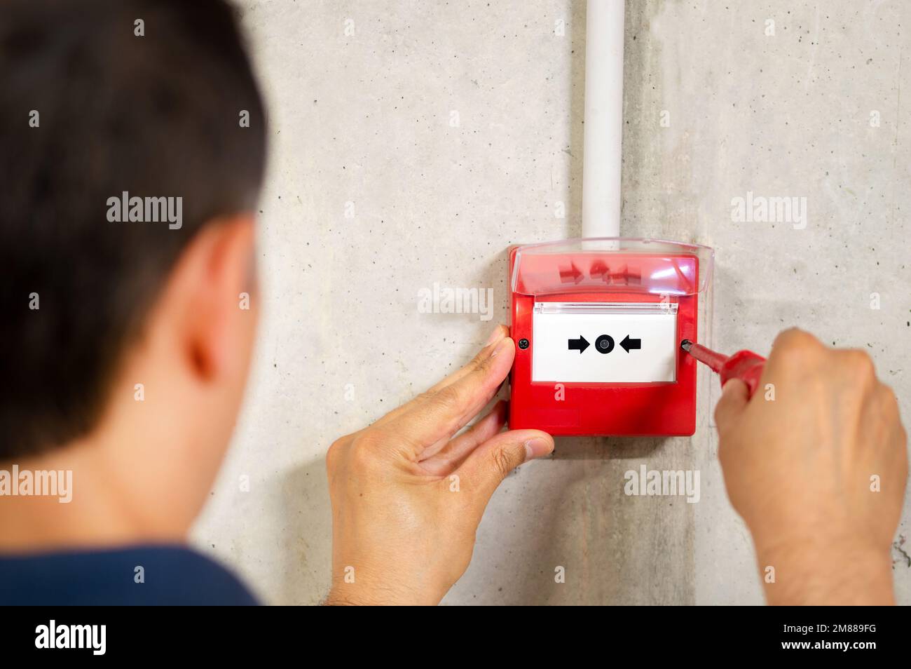 A back view of electrician installing fire alarm system Stock Photo - Alamy