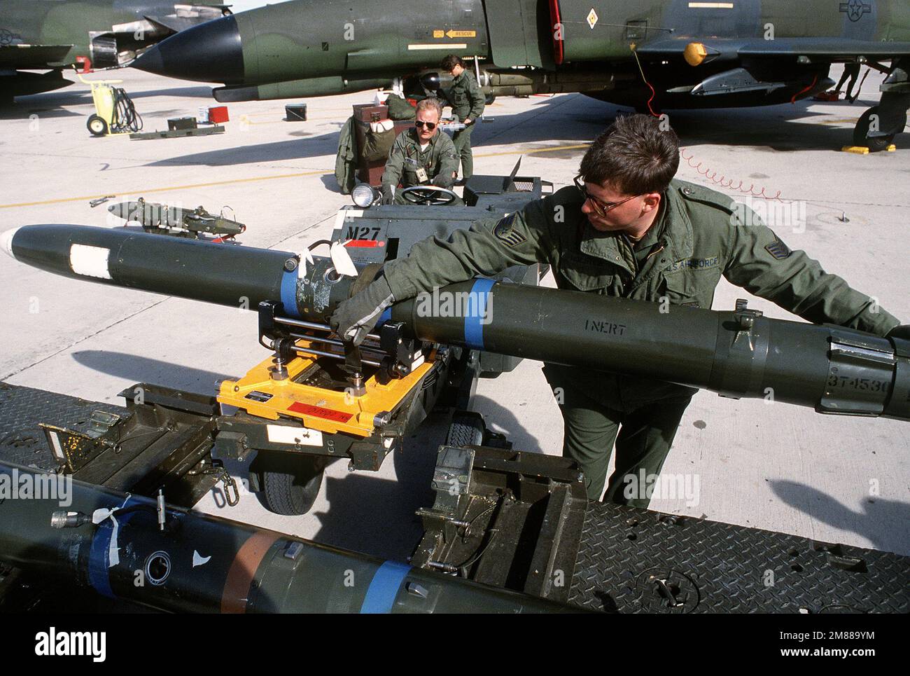 Ground crewmen of the 37th Tactical Fighter Wing maneuver an inert AGM-45 Shrike missile on the ...