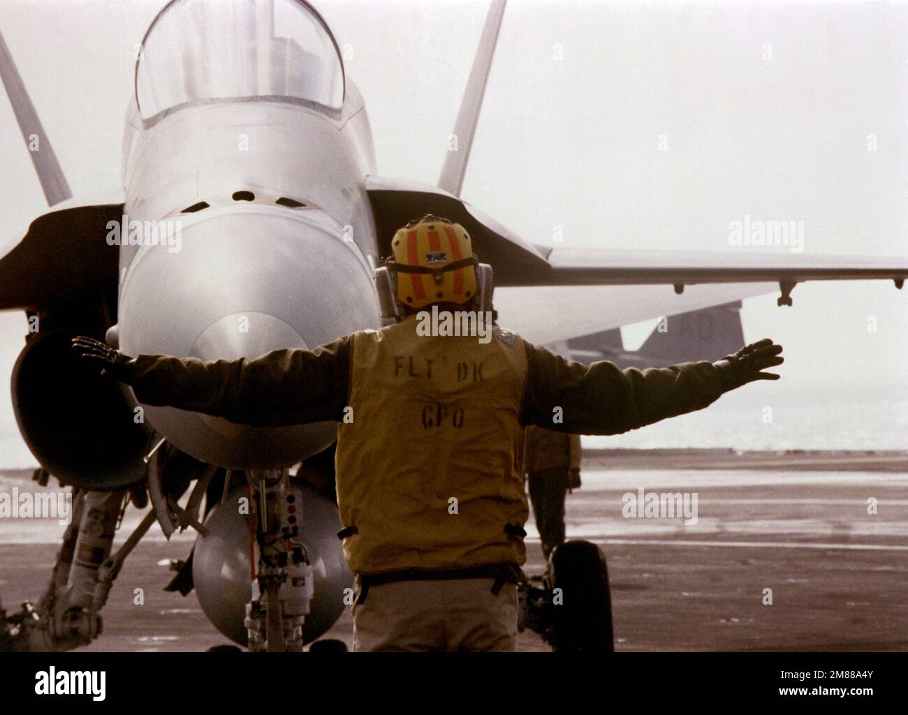 A plane director signals instructions to the pilot of an an F-18 Hornet ...