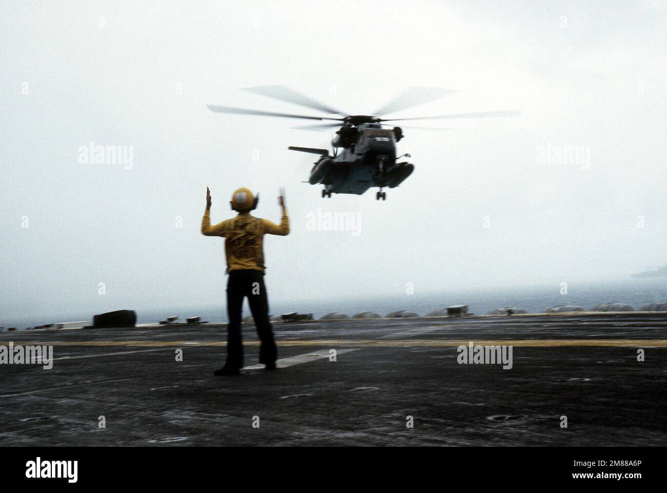 A plane director signals landing instructions to the pilot of a ...