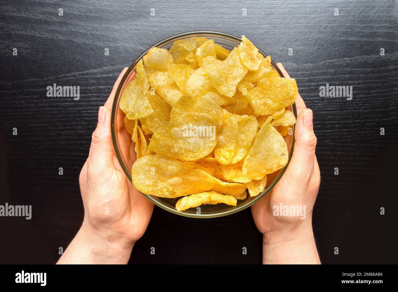 Top view shot of a hands giving bowl of potato chips on black ...