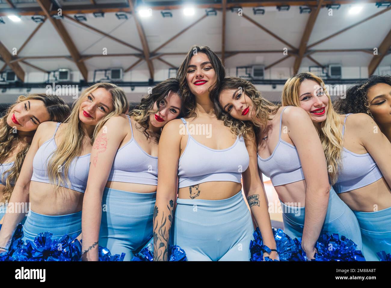 Group of cheerleaders is captured in a playful pose, resting their ...