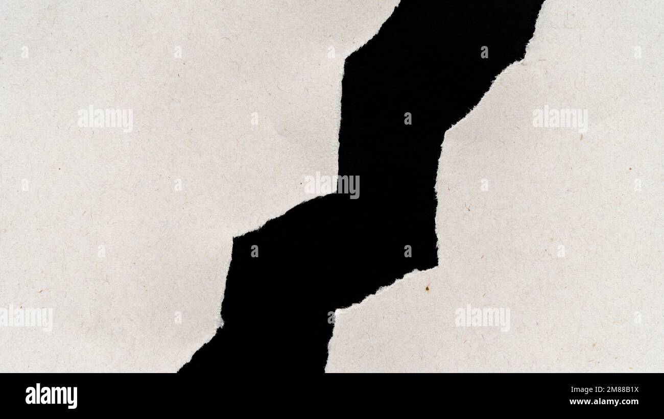 A macro shot of a torn paper with rough edges, on a black background ...