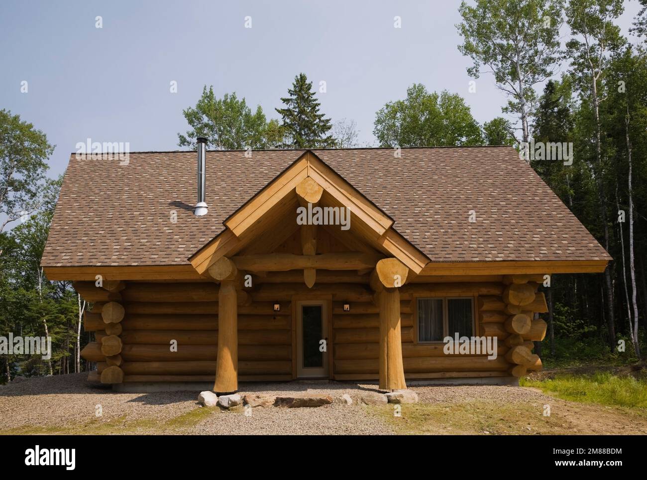 Handcrafted Eastern white pine cottage style log home facade in summer ...