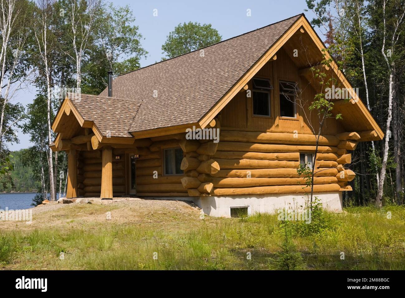 Handcrafted Eastern white pine cottage style log home facade in summer ...