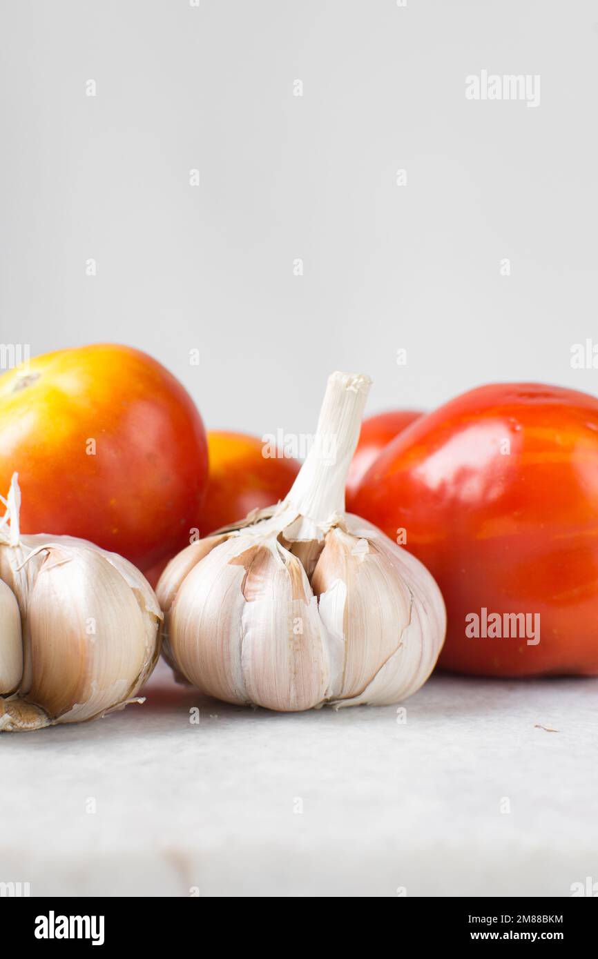 Garlic bulbs and tomatoes on a marble tray, raw garlic and tomatoes for ...