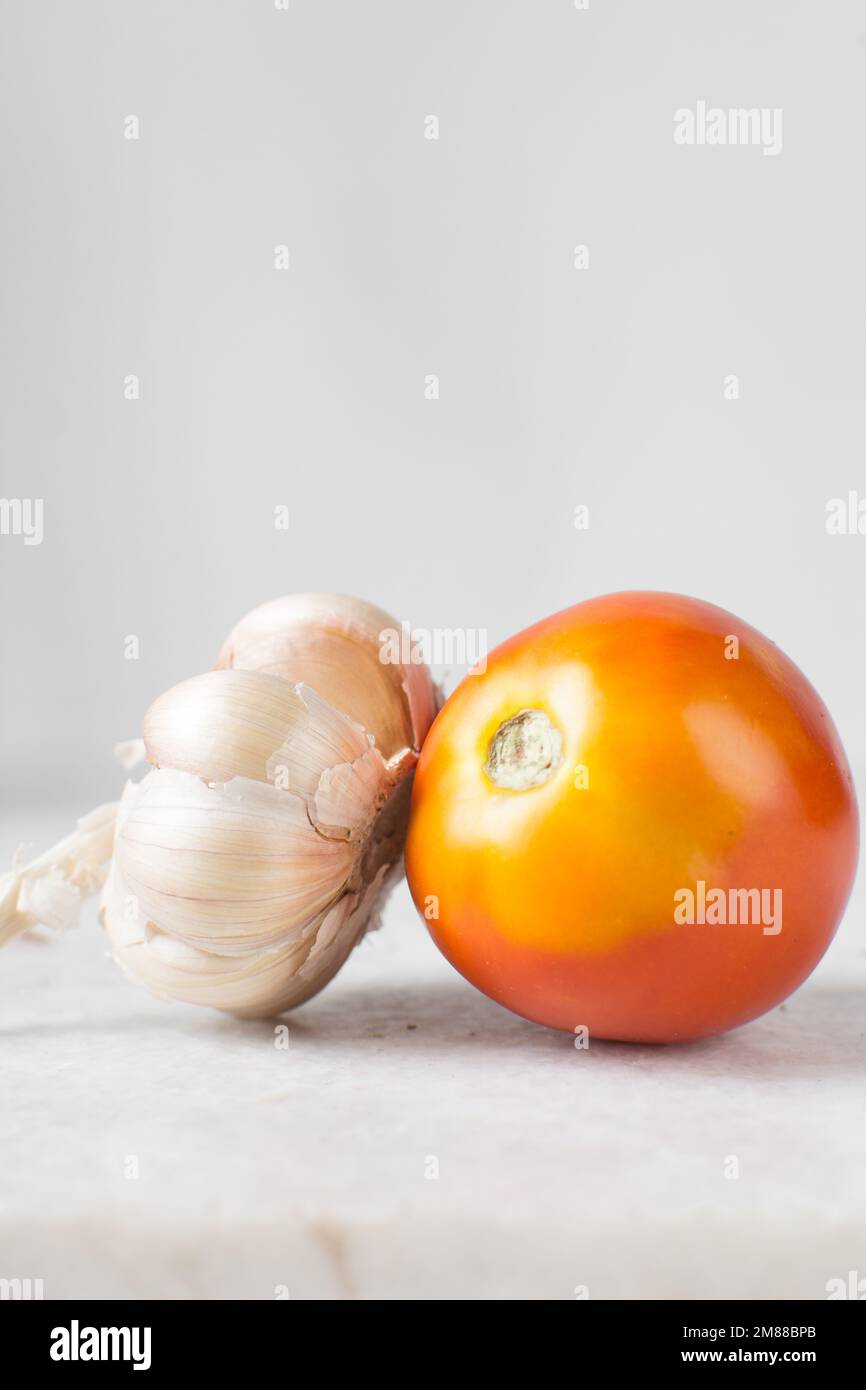 Garlic bulbs and tomatoes on a marble tray, raw garlic and tomatoes for ...