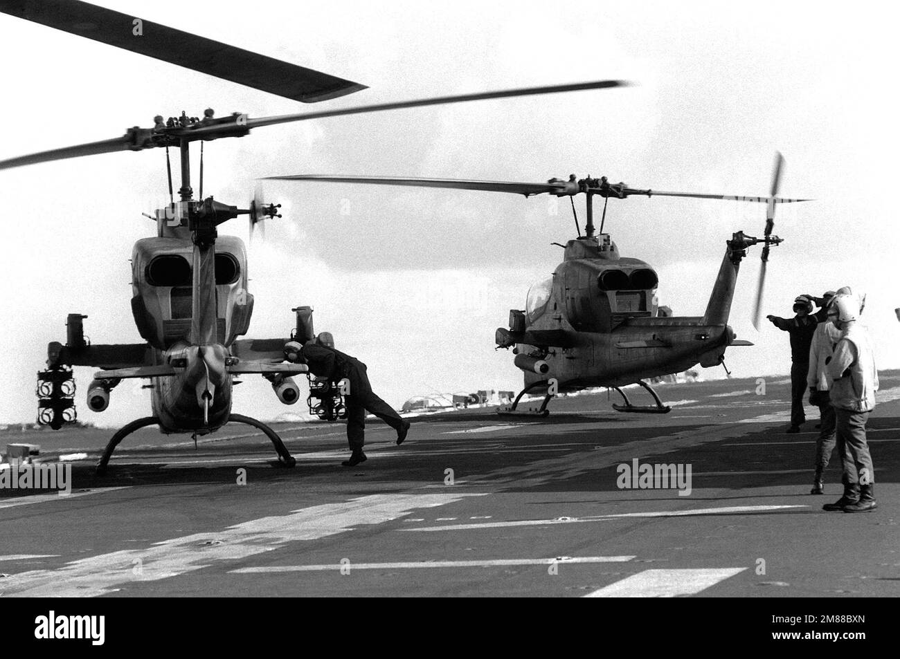 A pair of AH-1T Sea Cobra helicopters idle on the flight deck of the ...