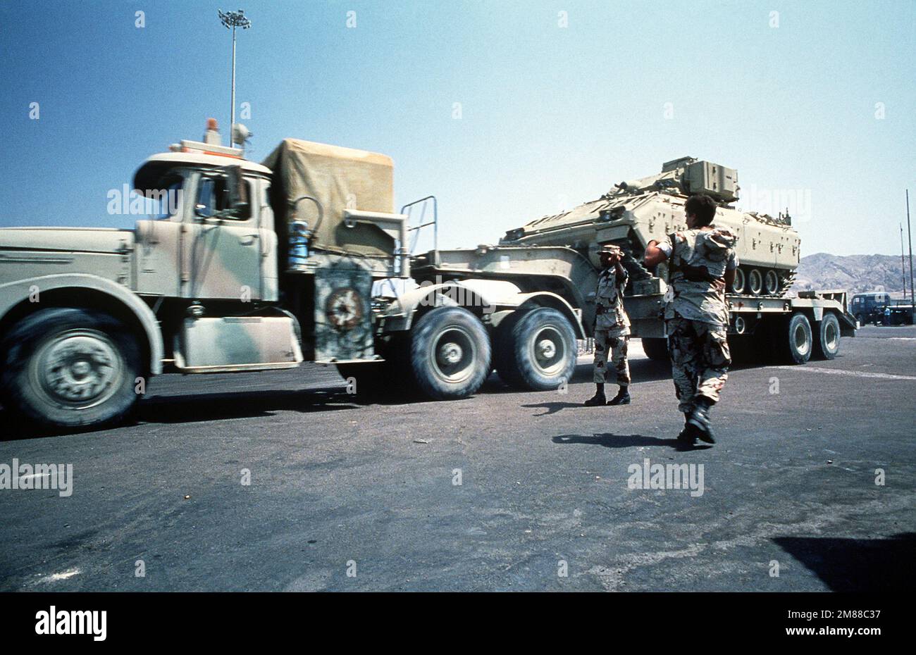 U.S. military personnel direct the driver of a tank transporter which ...